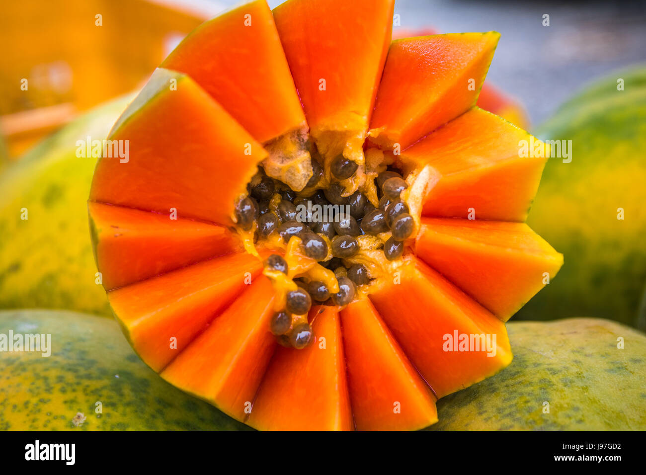 Closeup of bright orange papaya cut artfully with brown seeds ...