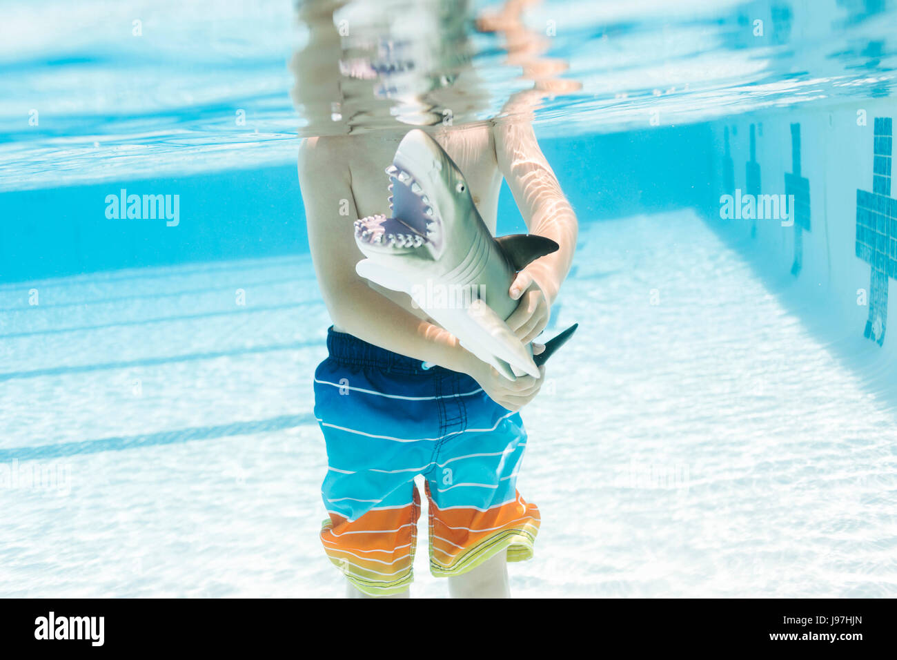 Boy (6-7) playing with toy shark in swimming pool Stock Photo - Alamy