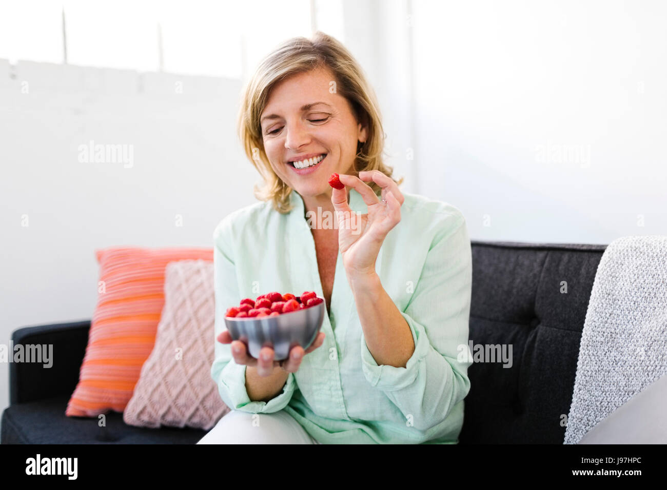 Mature woman eating raspberries Stock Photo - Alamy