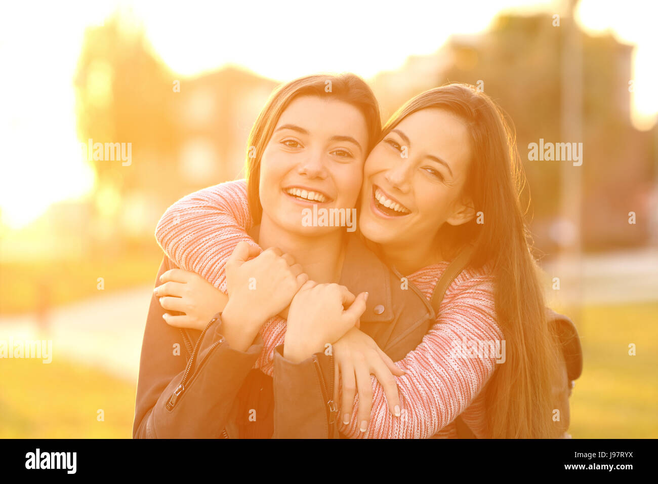 Front view portrait of two happy friends laughing and posing looking at ...