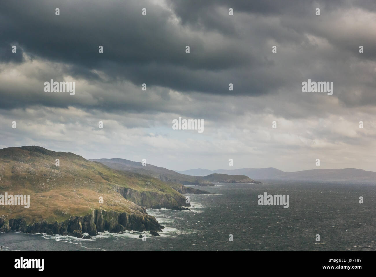 a beautiful view of the irish sea side from a cliff with the cloudy sky ...
