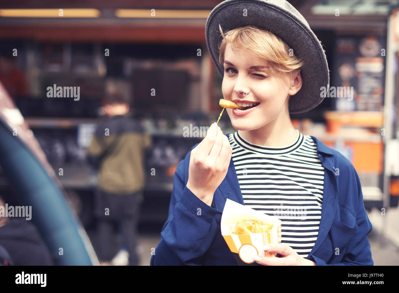 Portrait of young woman with fries winking Stock Photo - Alamy