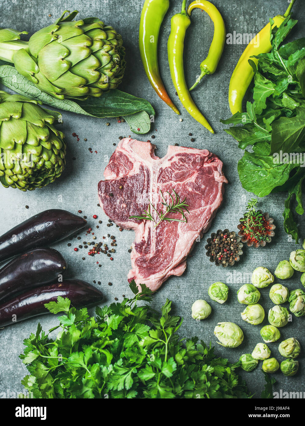 Raw beef uncooked t-bone steak with green vegetables and spices Stock ...