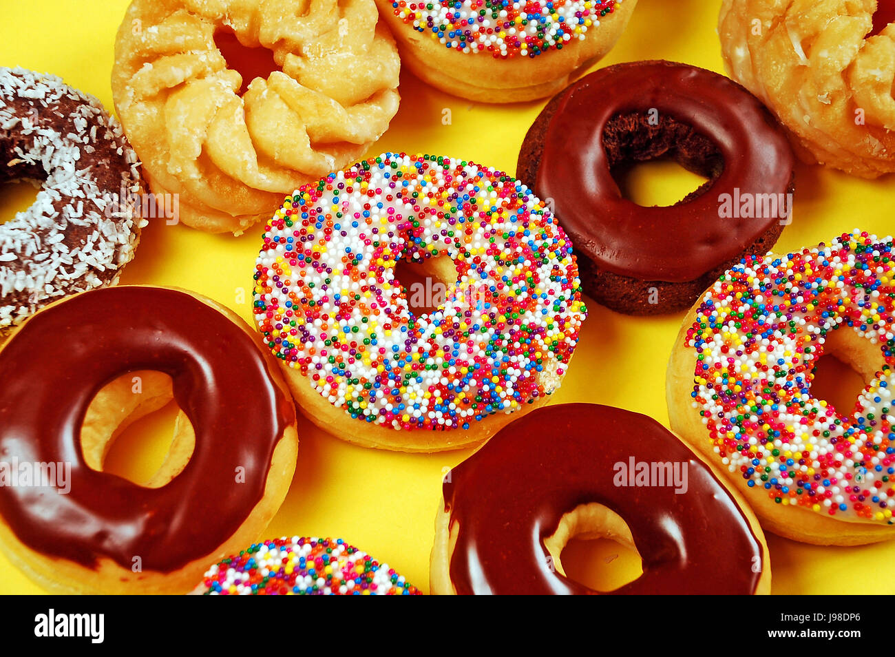 Assorted selection of donuts on yellow background Stock Photo - Alamy