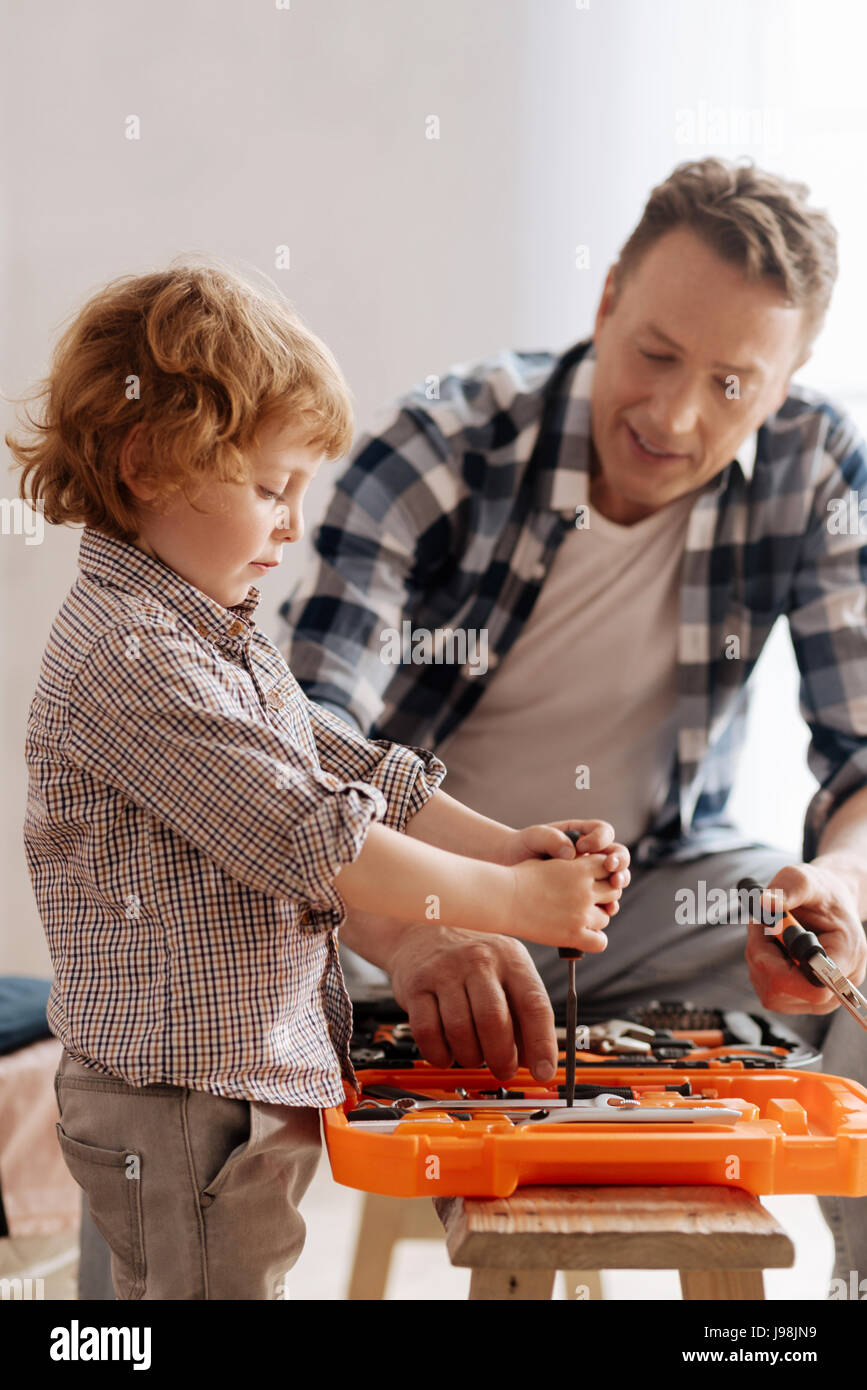 Handsome positive man taking tools Stock Photo - Alamy