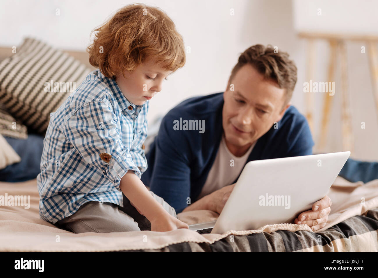 Serious kid looking downwards at computer Stock Photo - Alamy
