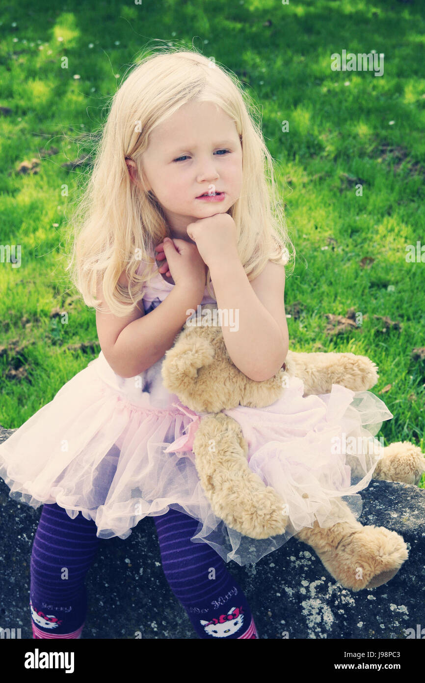 Little three year old girl with long curly blonde hair sitting on the ...
