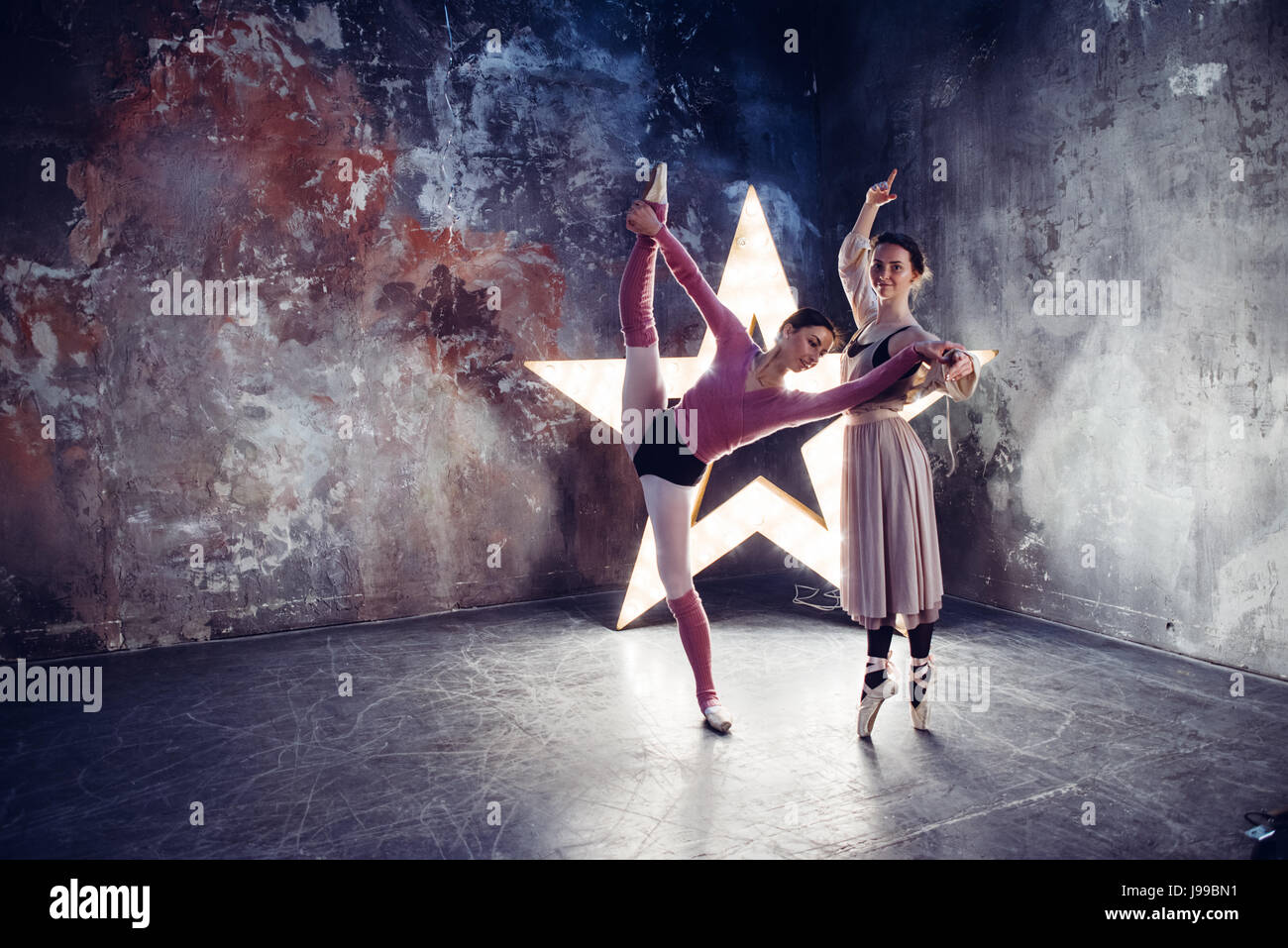Ballet dancer practice exercise in front of a illuminated star on a dak ...