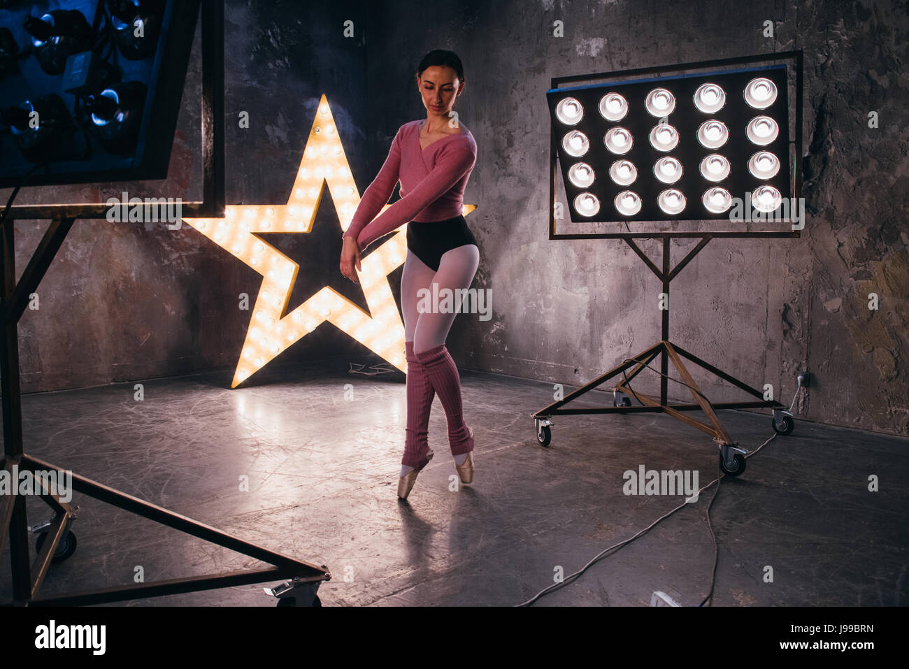 Ballet dancer practice exercise in front of a illuminated star on a dak ...