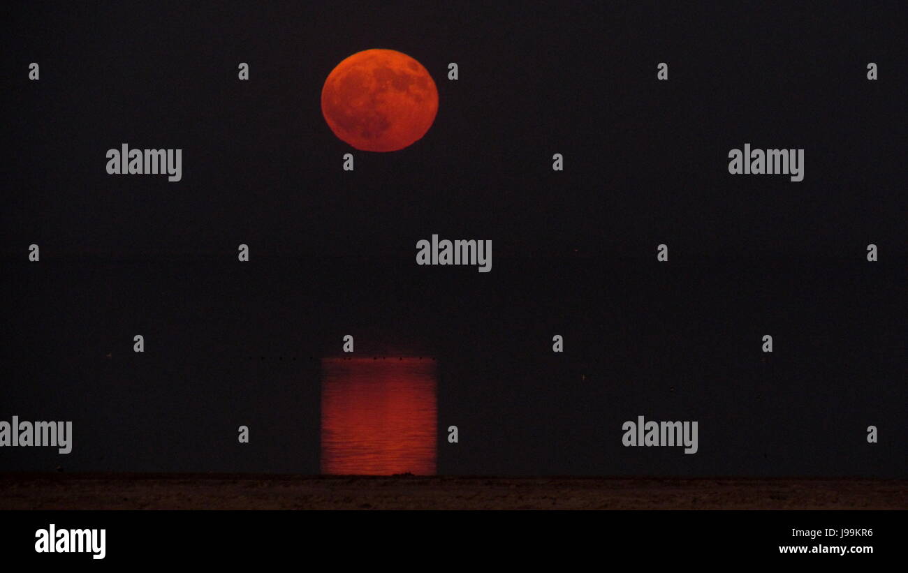 Red Harvest moon reflected on the Salton Sea in Southern California at ...