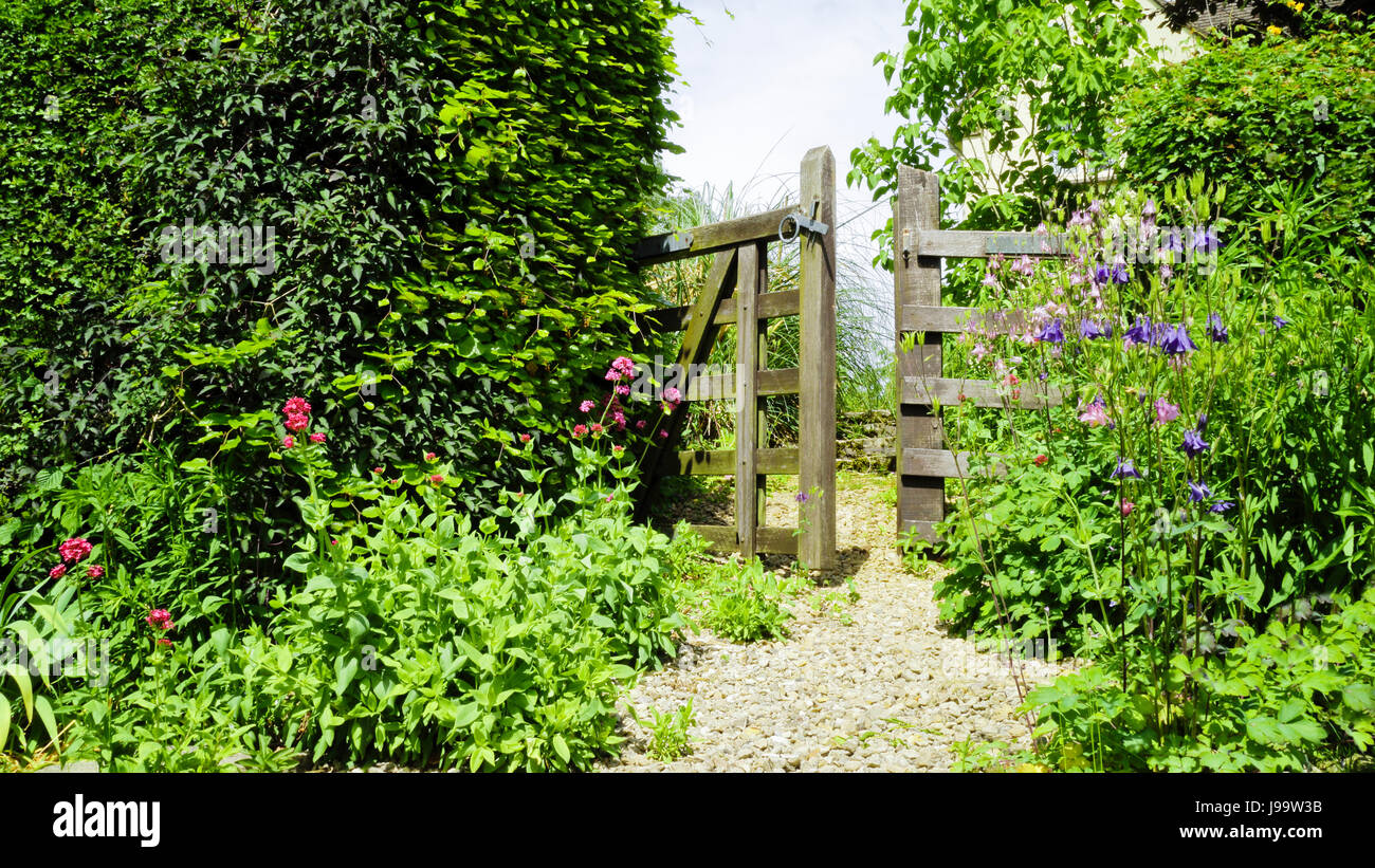Open wooden gate in an English cottage flowering garden, on a summer ...