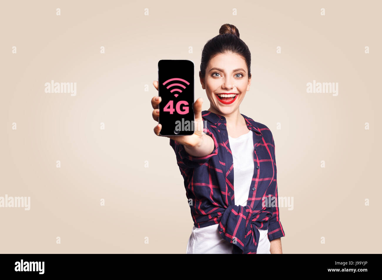 Young beautiful woman in casual style holding phone looking at camera ...