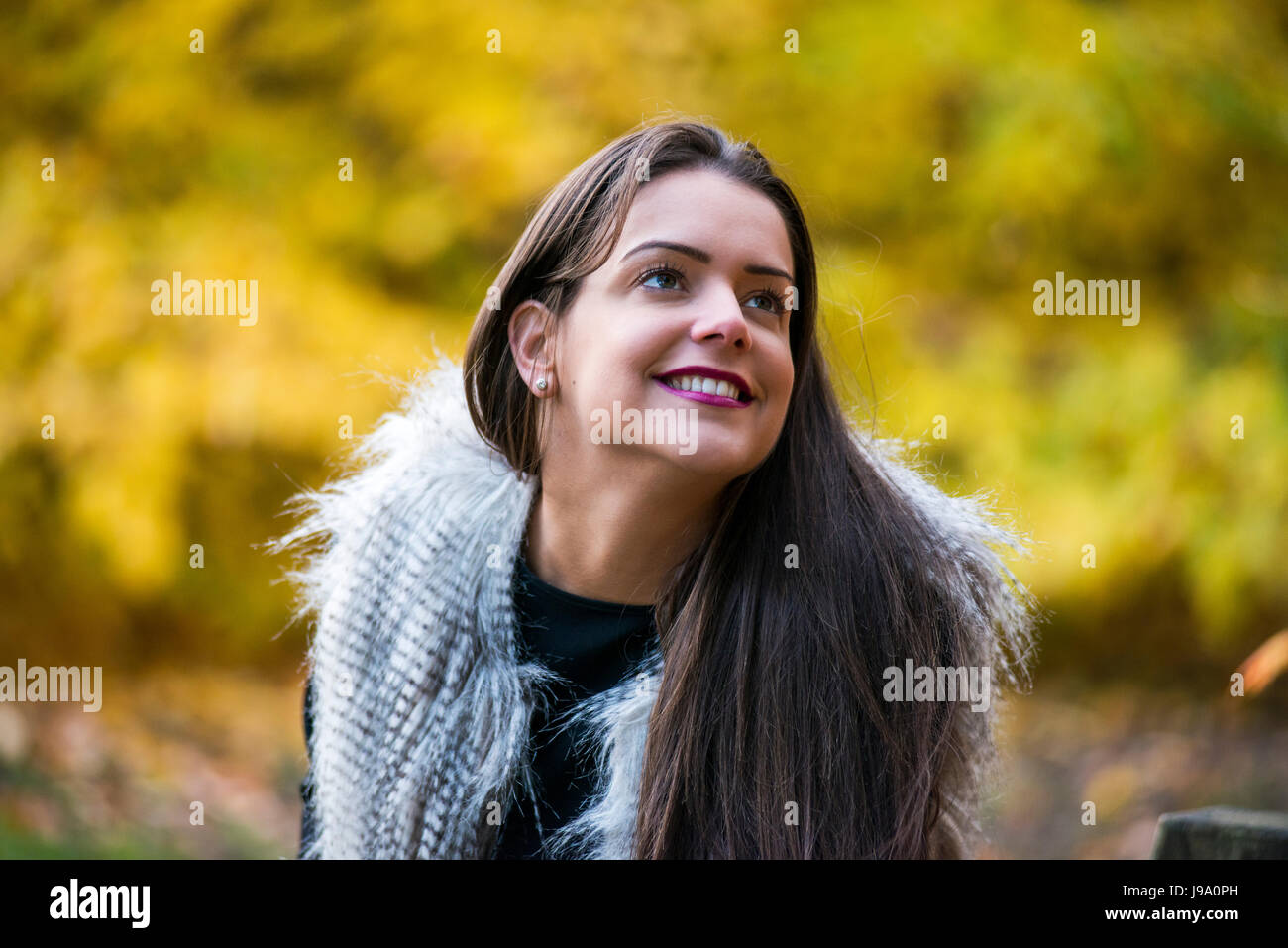 Young lady enjoying warm autumn colours in the woodlands surrounded by ...