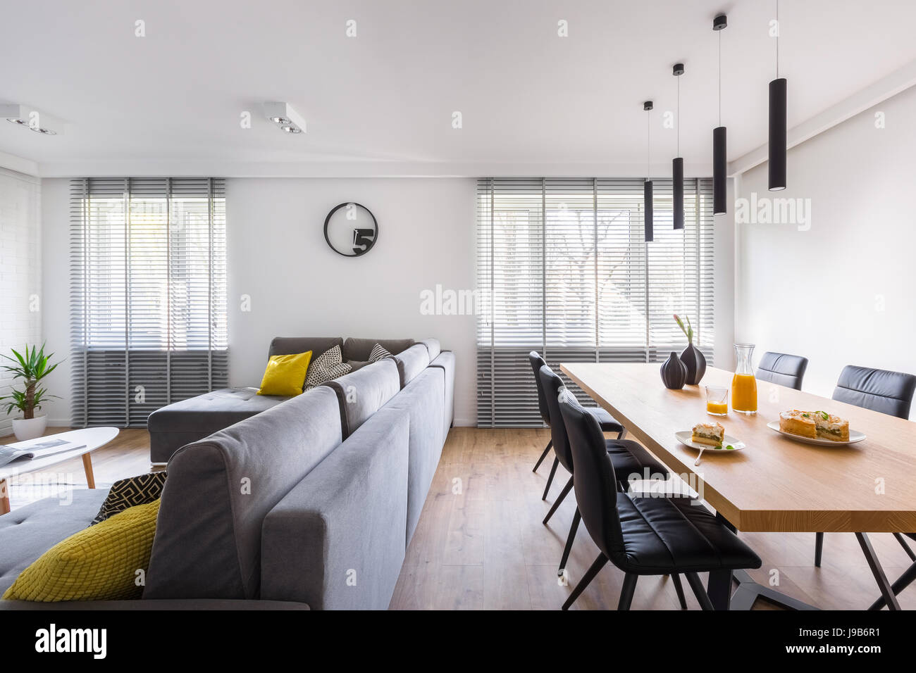 Modern home interior with communal table, black chairs and gray extra ...