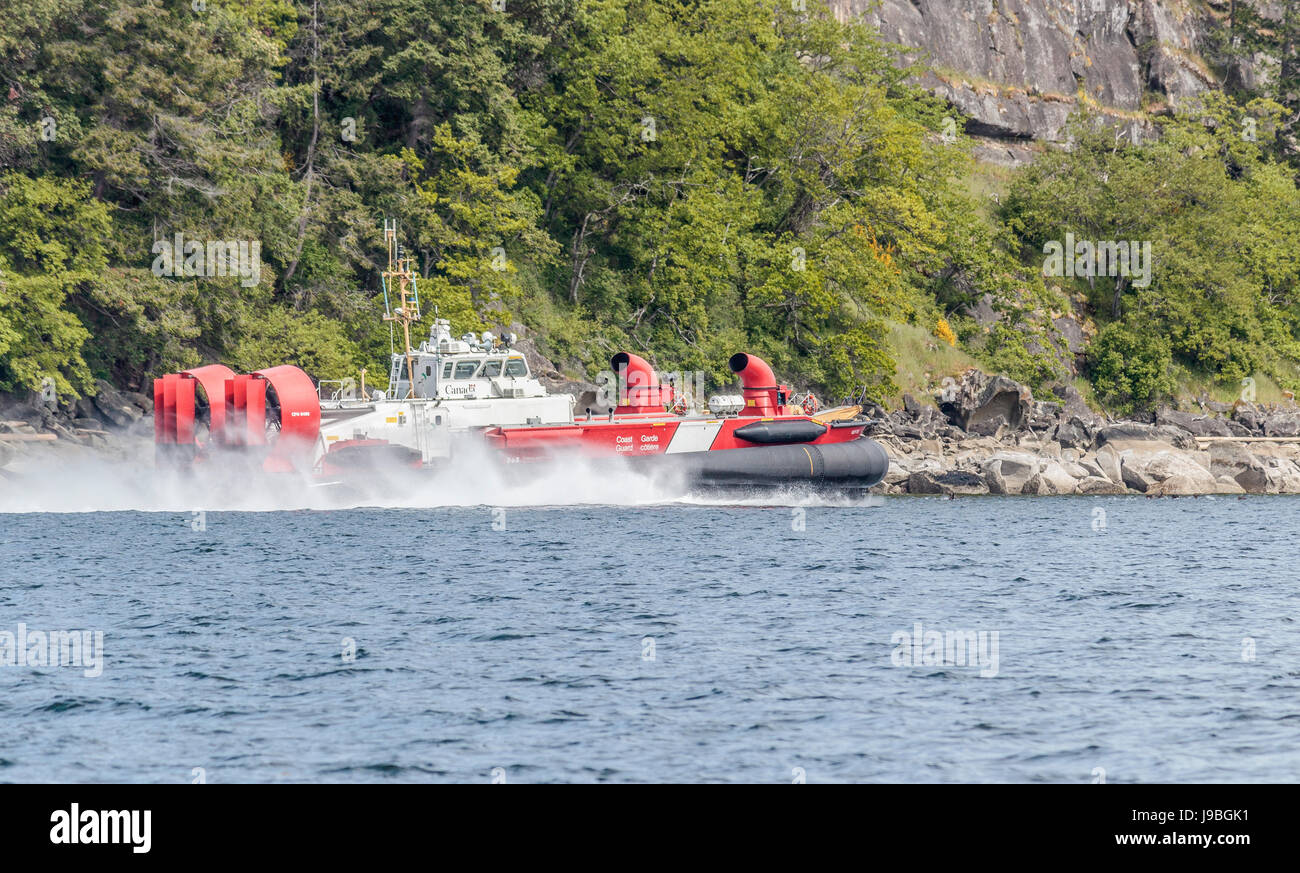 A Canadian Coast Guard hovercraft speeds alongside the shoreline of ...