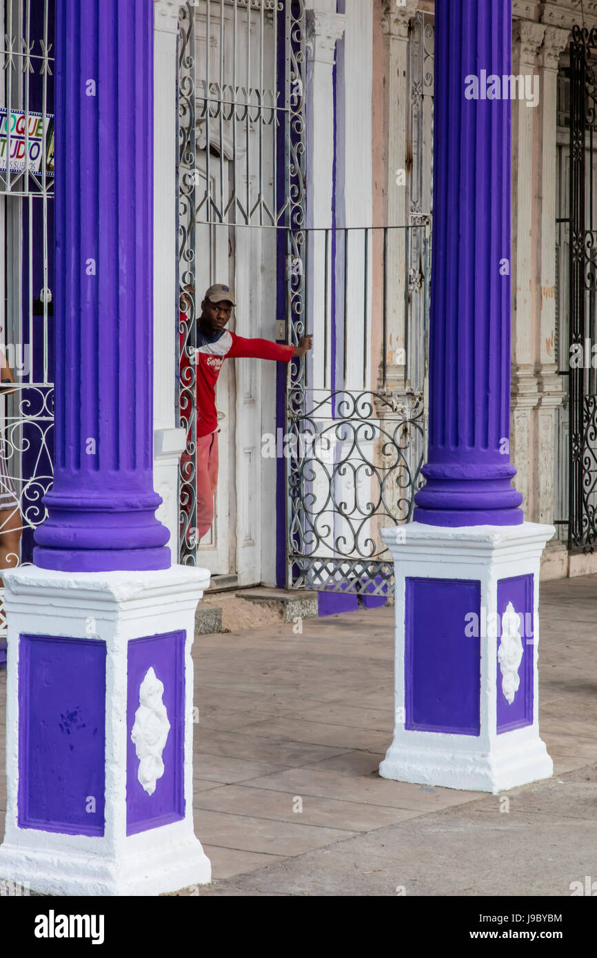 A shop owner between purple pillars - CIENFUEGOS, CUBA Stock Photo - Alamy