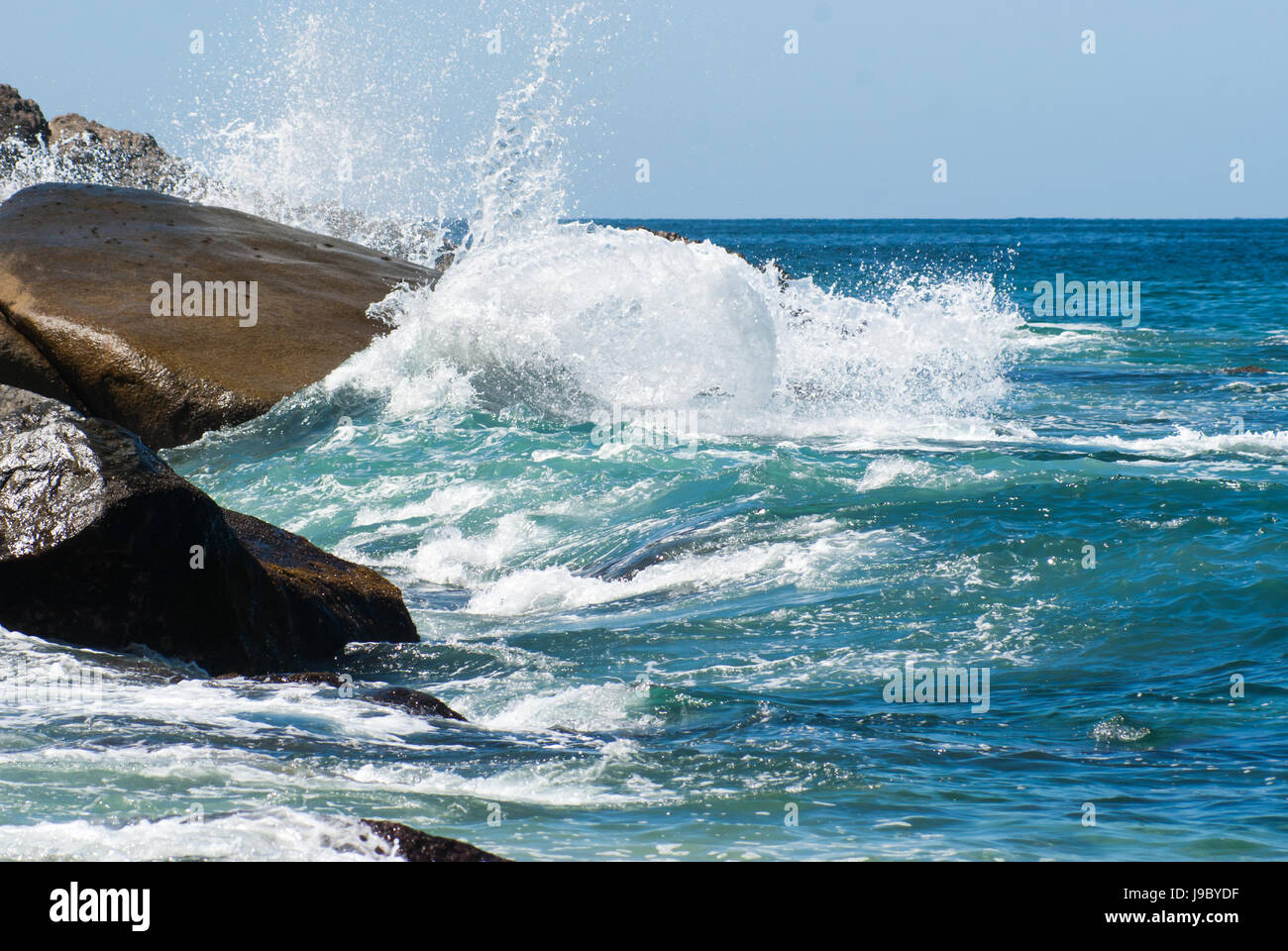 A wave exploding on a rocky shore in white spray. Very active wave ...