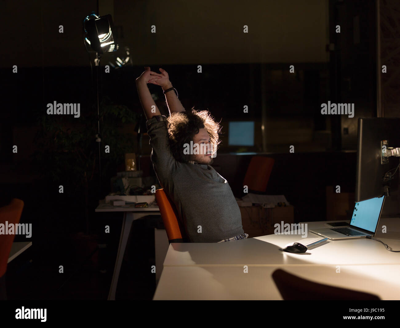 Young man working on computer at night in dark office. The designer ...
