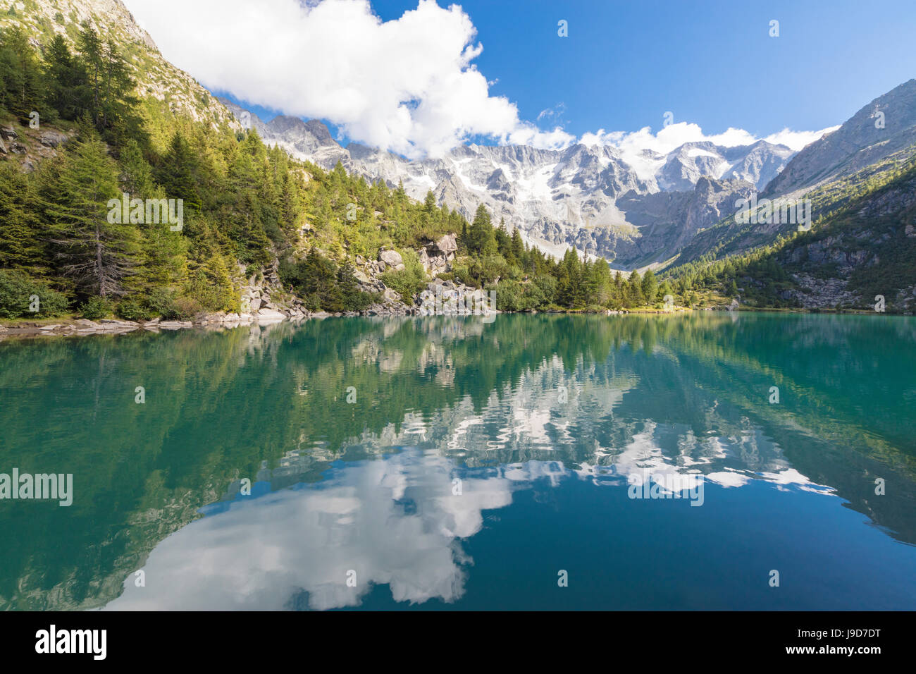 Rocky peaks and woods are reflected in Lago Aviolo, Vezza d'Oglio ...