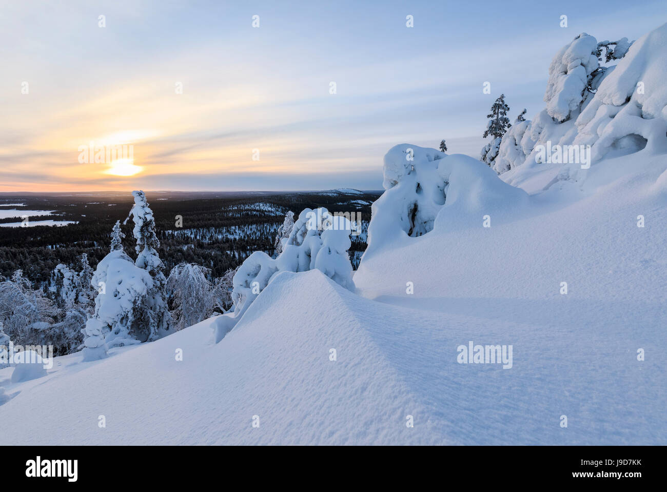 The sun frames the snowy landscape and woods in the cold arctic winter ...