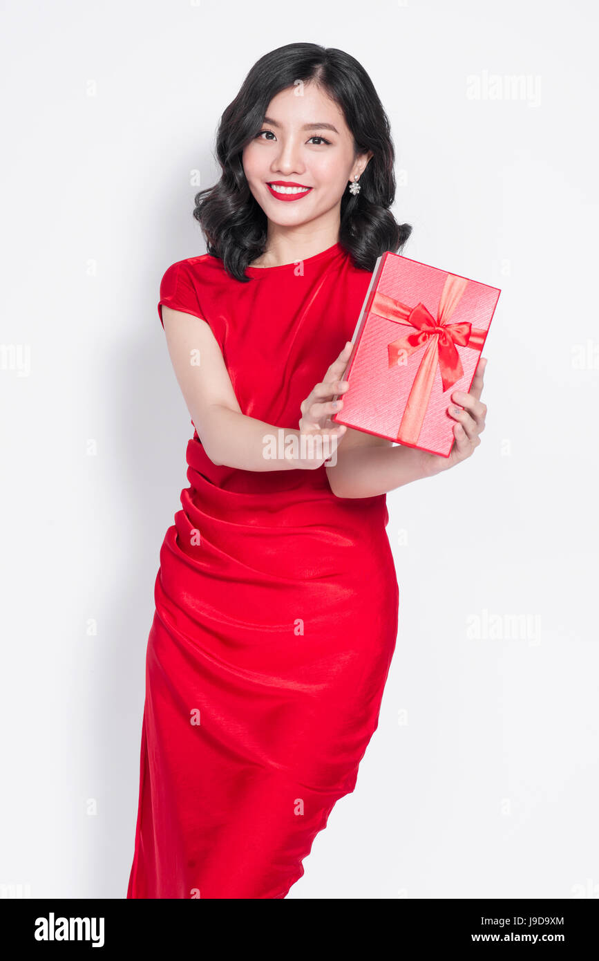 Pretty young glamorous asian woman dressed in red dress with a present ...