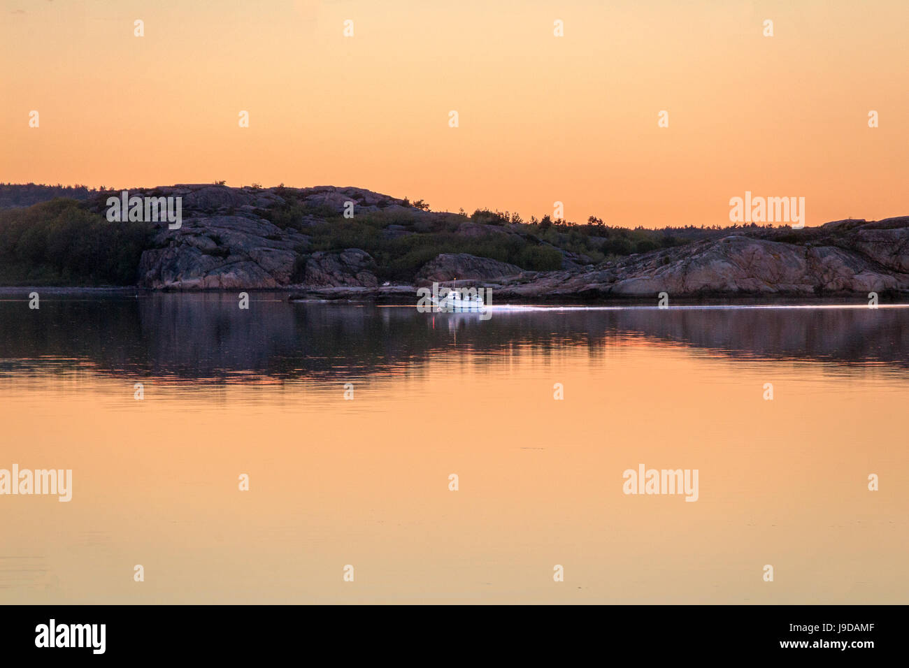 Boat driving in the sunset over mirror clear ocean Stock Photo - Alamy