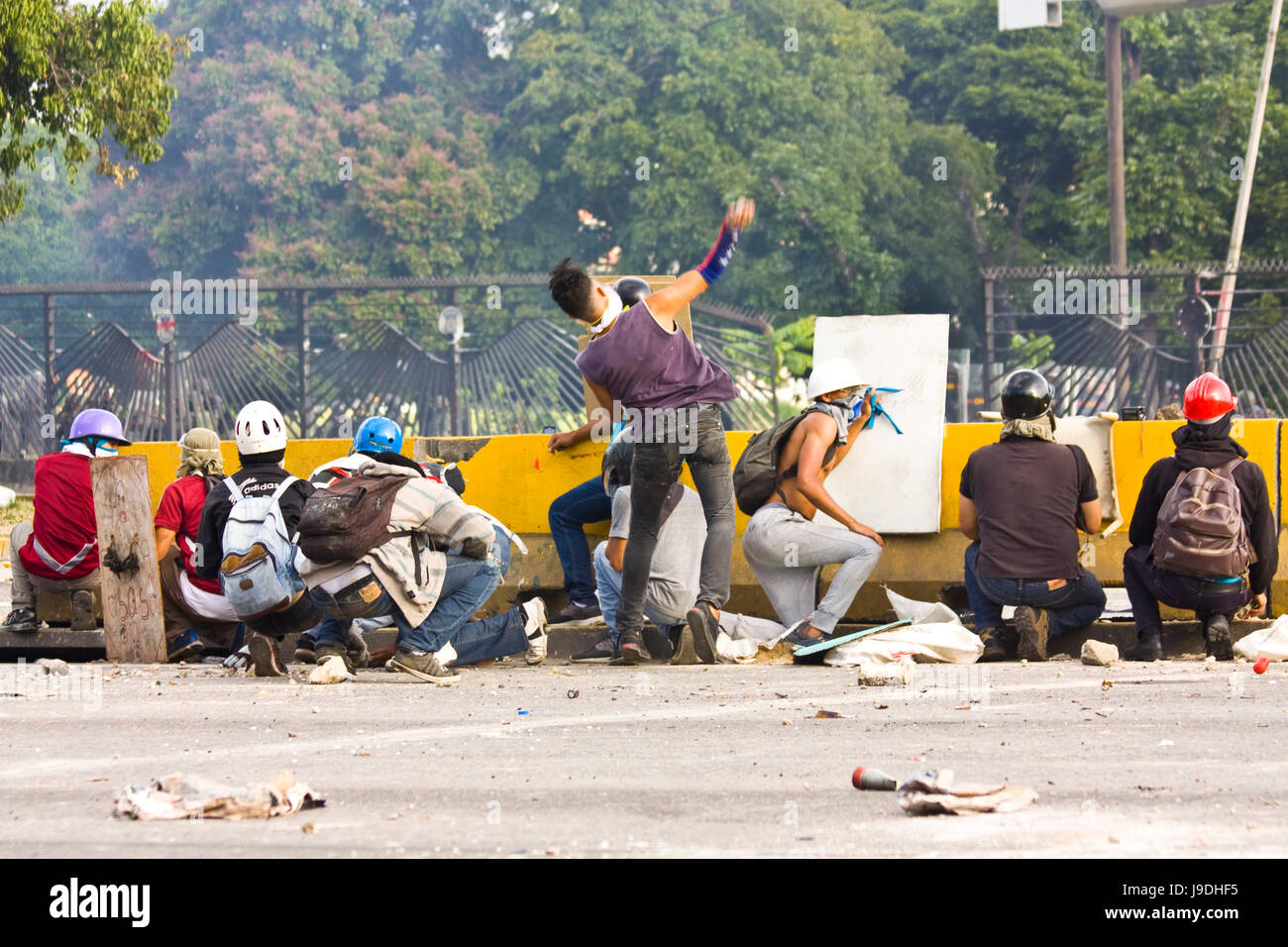 A demonstrator throws rocks during a protest on a highway in Caracas ...