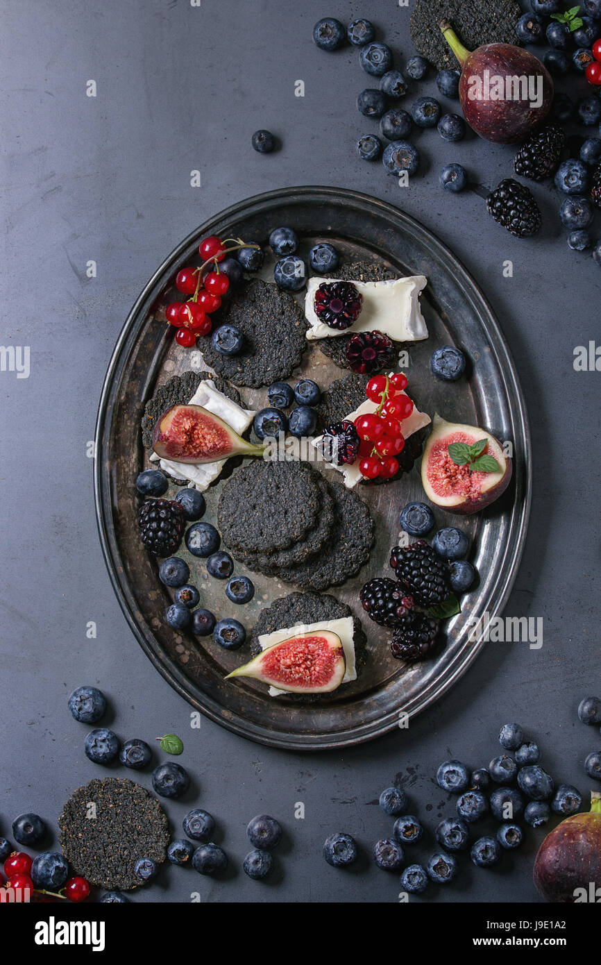 Black crackers with cheese and berries Stock Photo - Alamy