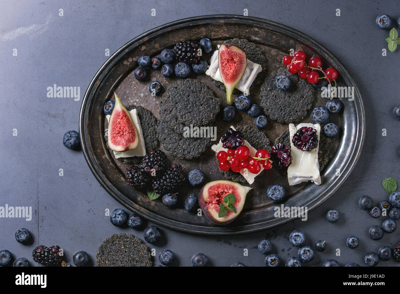 Black crackers with cheese and berries Stock Photo - Alamy