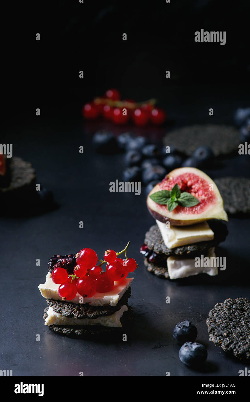 Black crackers with cheese and berries Stock Photo - Alamy