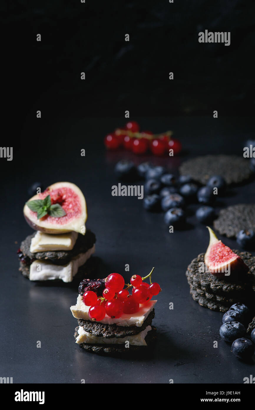 Black crackers with cheese and berries Stock Photo - Alamy