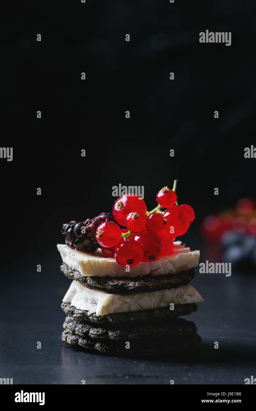 Black crackers with cheese and berries Stock Photo - Alamy
