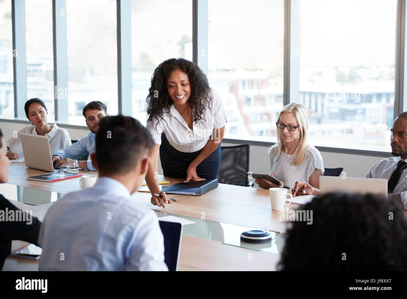Businesswoman Stands To Address Meeting Around Board Table Stock Photo ...