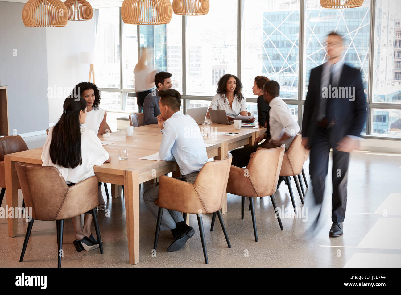 Group Of Businesspeople Sitting Around Table In Meeting Room Stock ...