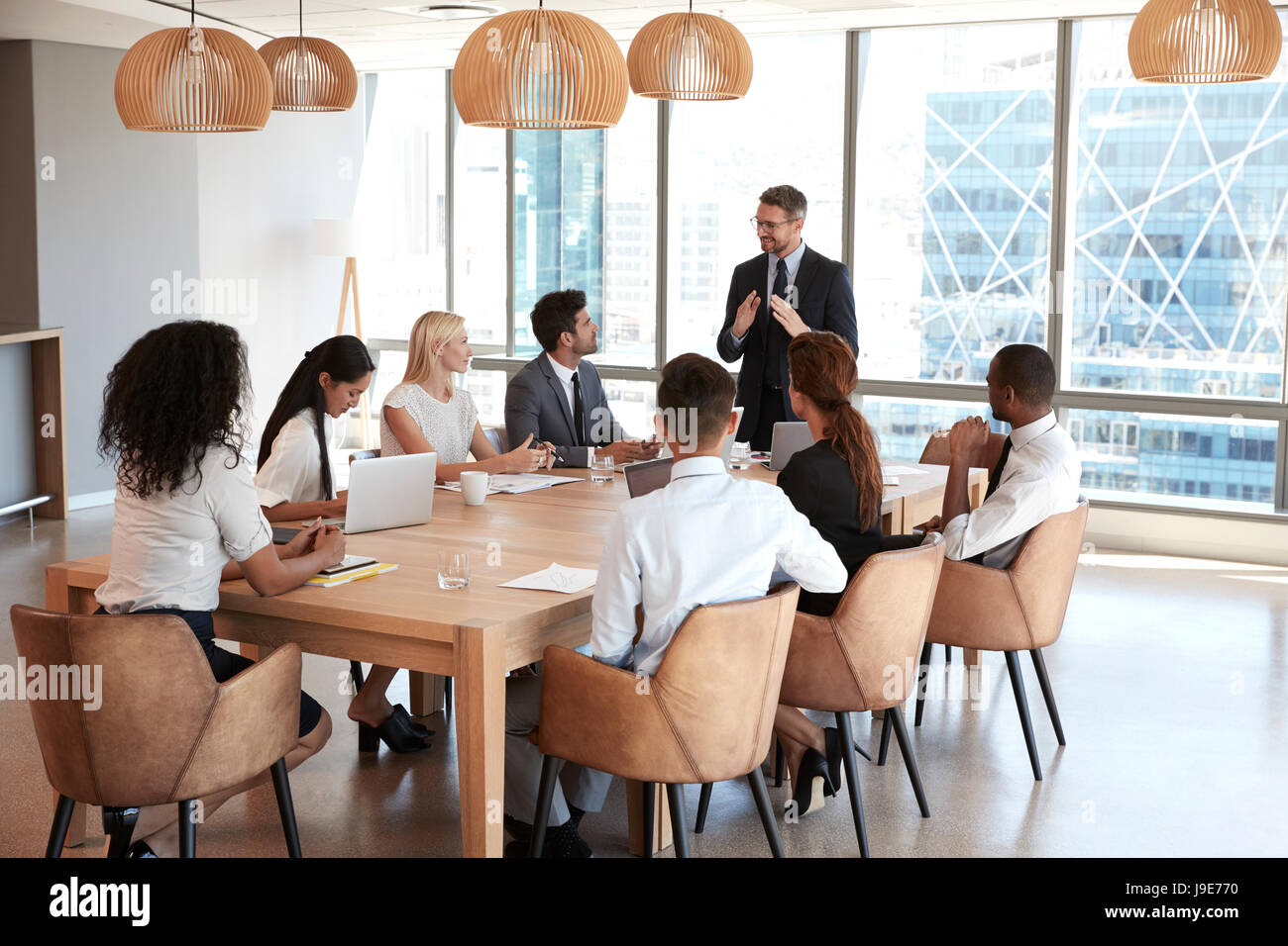 Businessman Stands To Address Meeting Around Board Table Stock Photo ...