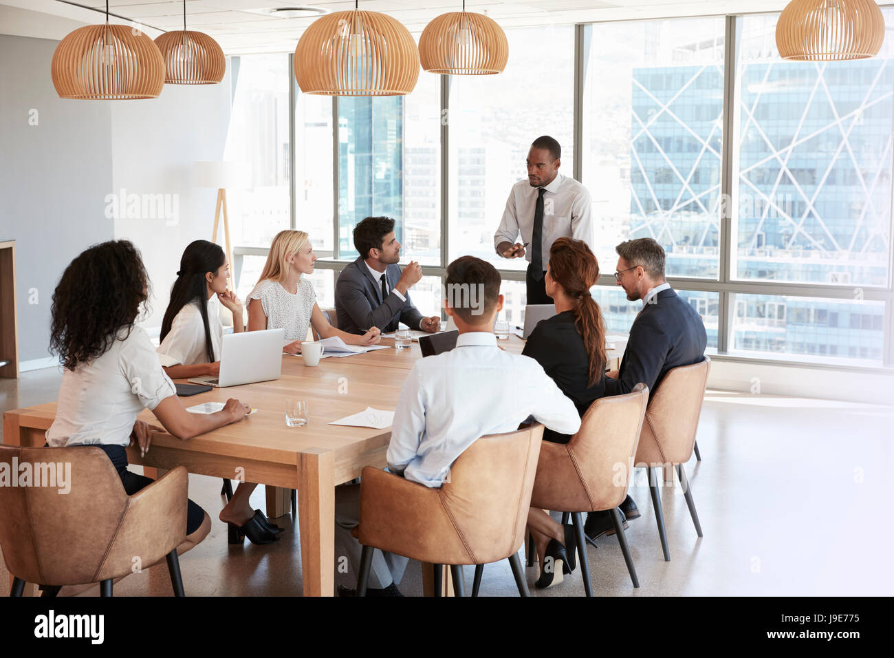 Businessman Stands To Address Meeting Around Board Table Stock Photo ...