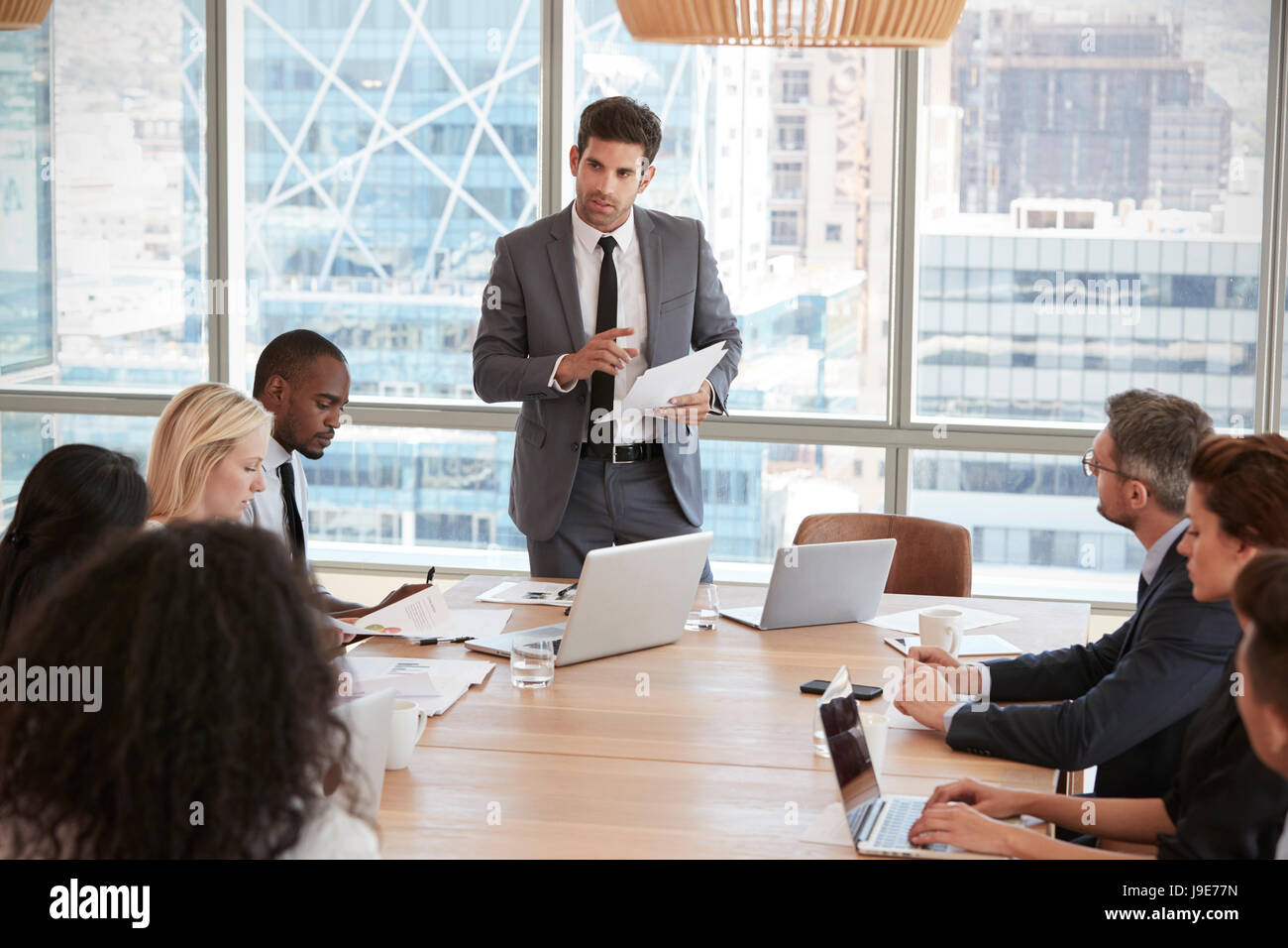 Businessman Stands To Address Meeting Around Board Table Stock Photo ...