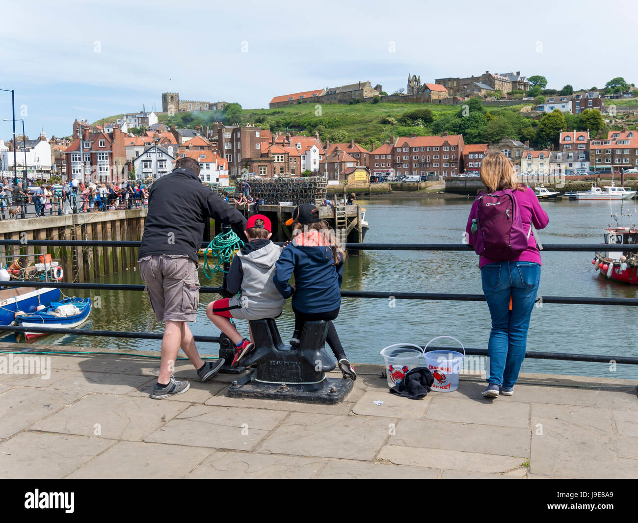 A family fishing for crabs in Whitby harbour on a sunny spring day ...