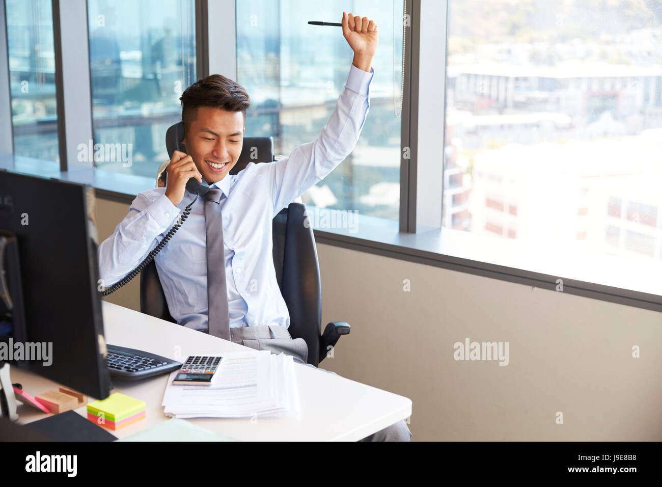Celebrating Businessman Making Phone Call At Desk In Office Stock Photo ...