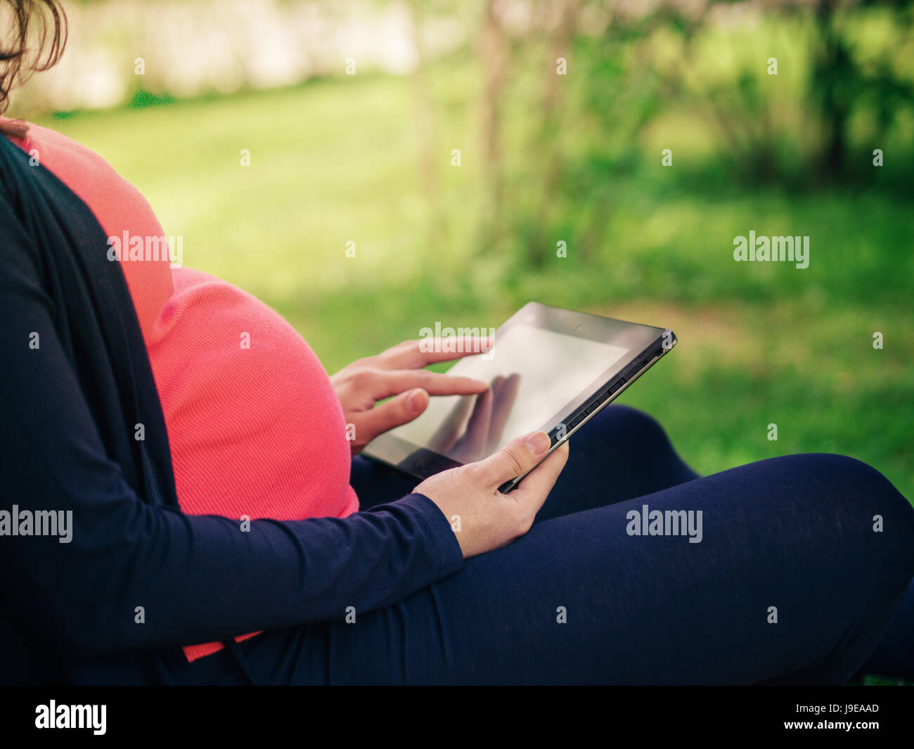 Close up view of pregnant belly and tablet pc. Pregnancy outdoors ...