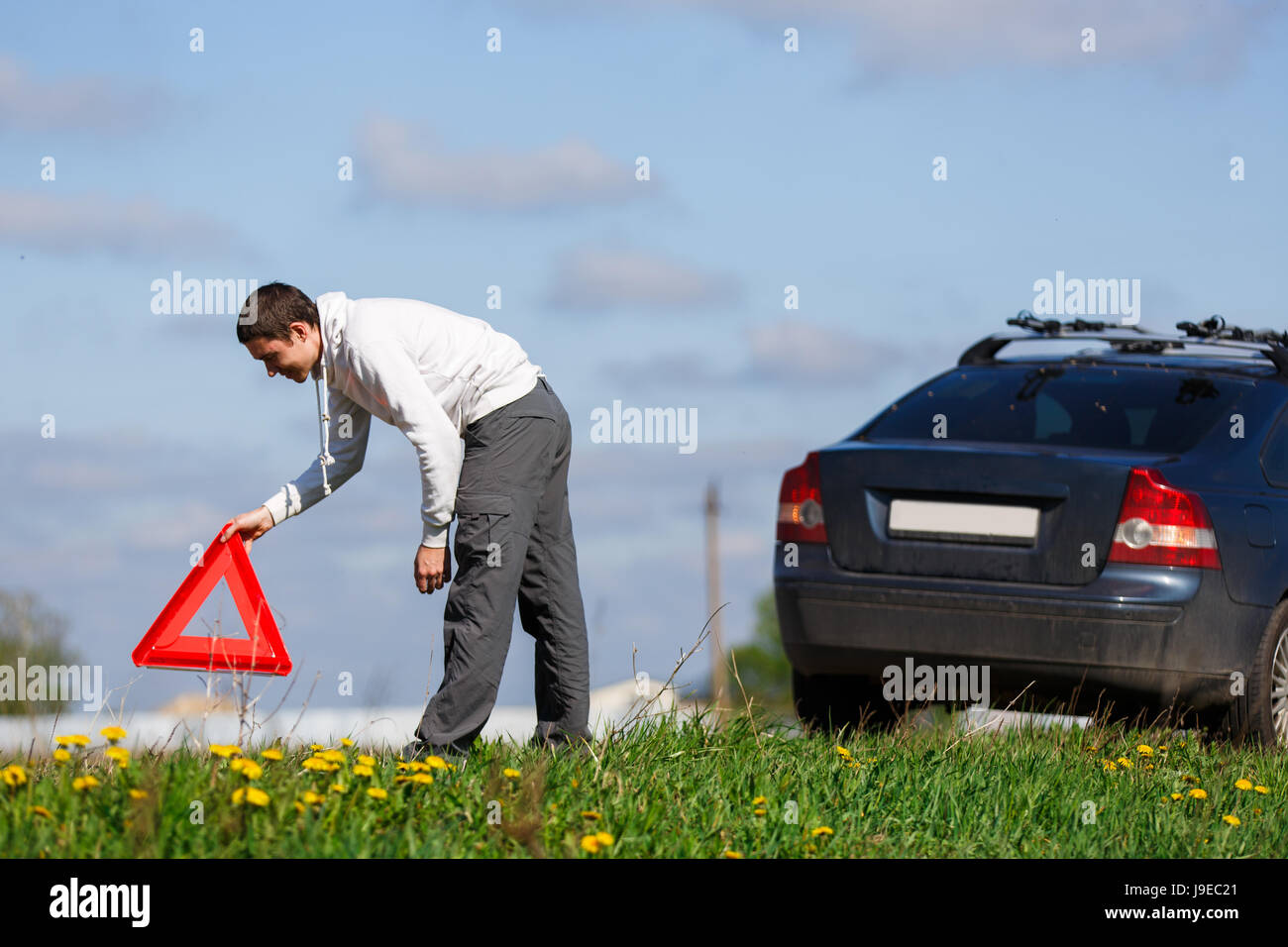 Man puts red warning triangle Stock Photo - Alamy