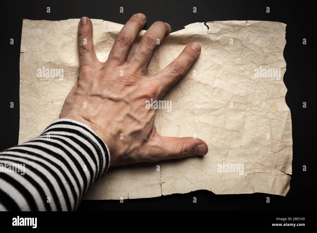 Sailor hand catching empty old crumpled paper sheet over black ...