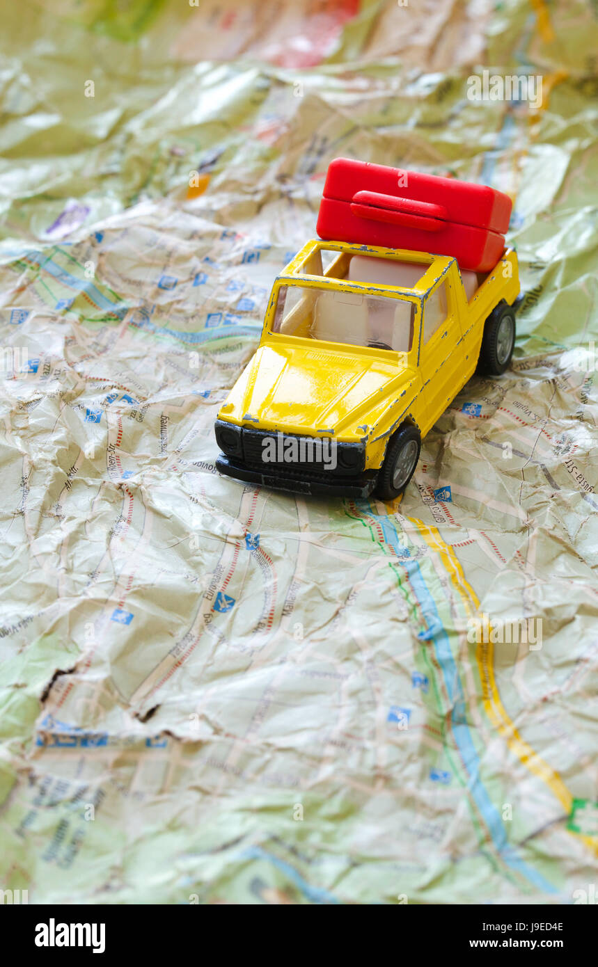 Mini yellow car with red suitcase on a jammed map. Closeup Stock Photo ...