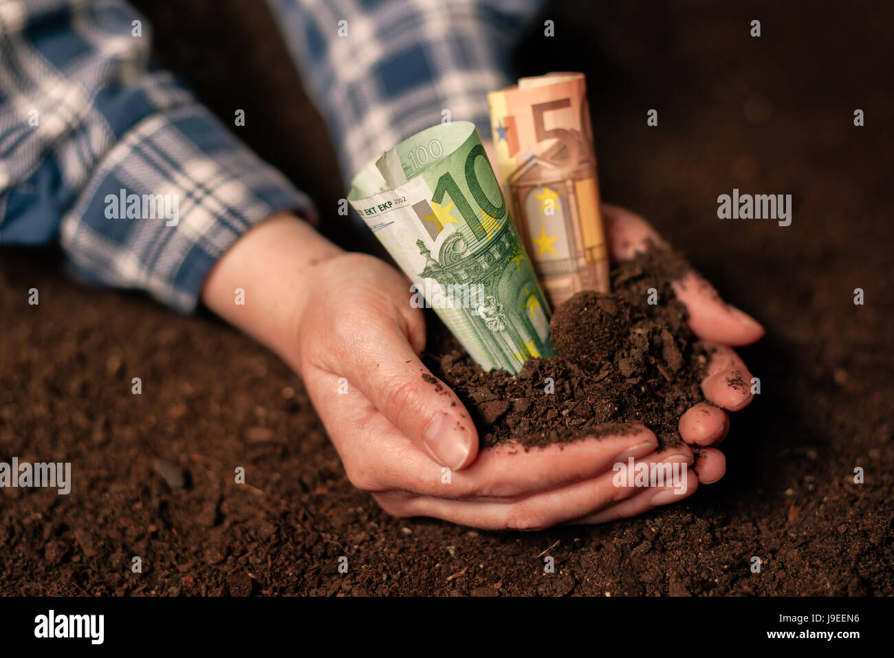 Hands with fertile soil and euro money banknotes, female farmer handful ...
