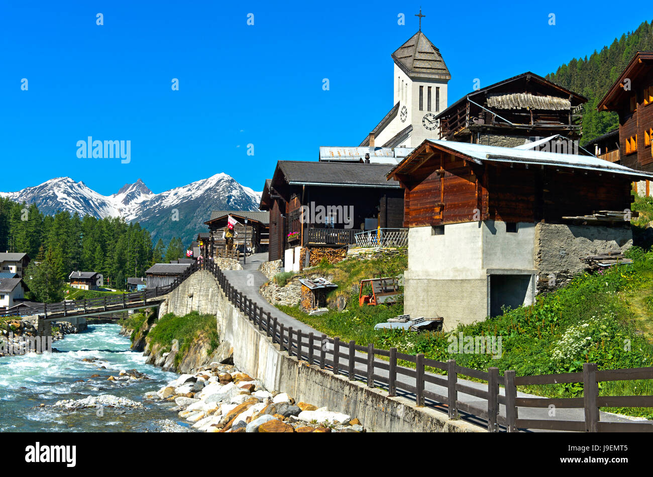 Listed mountain village with church rising above the river Lonza ...