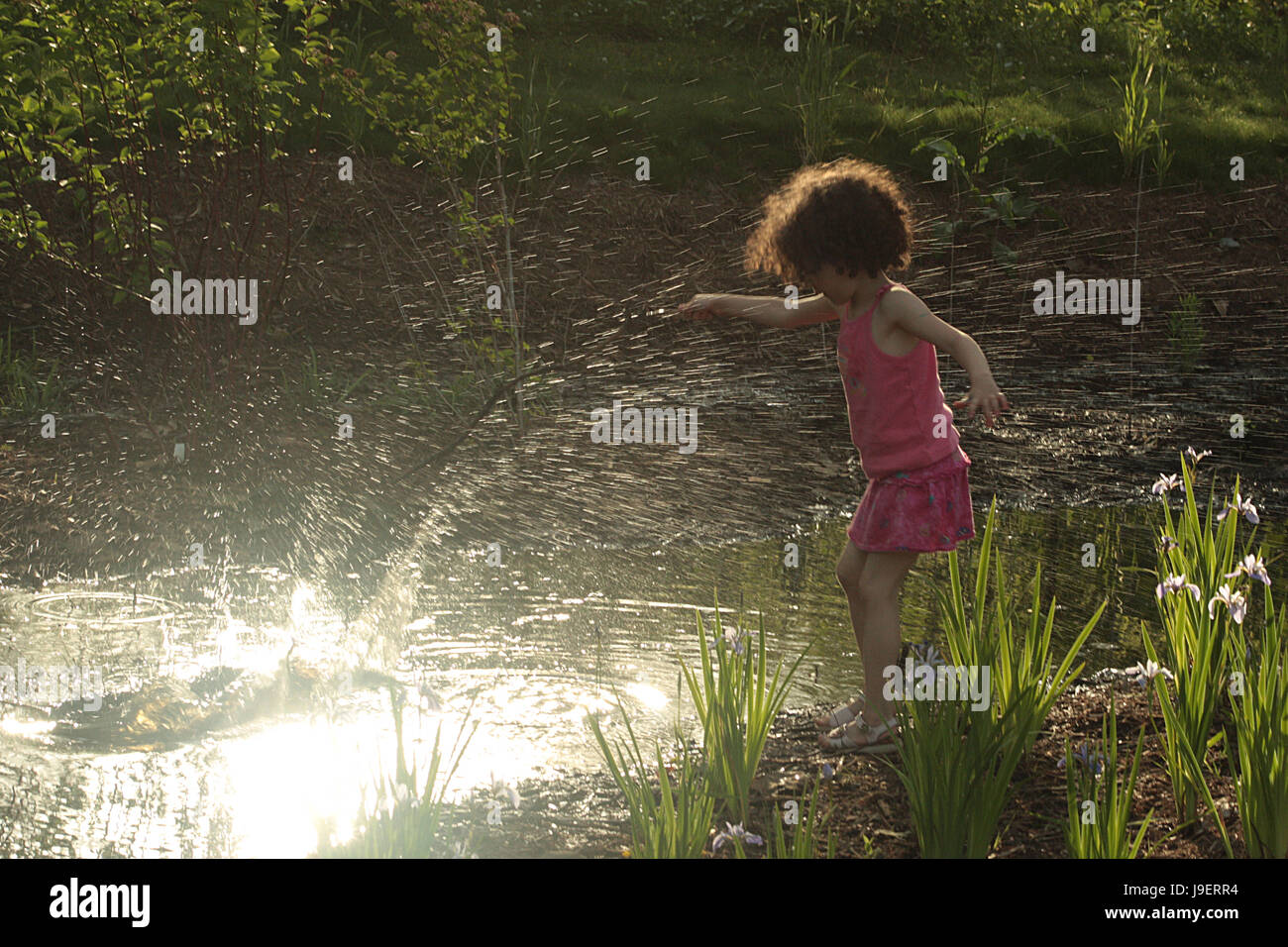 Little cute girl playing with stick in small pond Stock Photo - Alamy