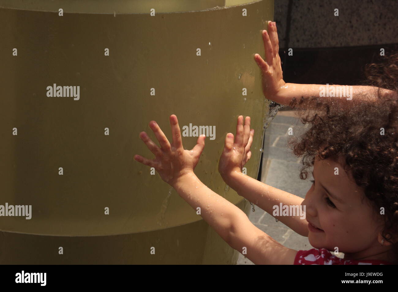 Little girl enjoying touching water from public water fountain Stock ...