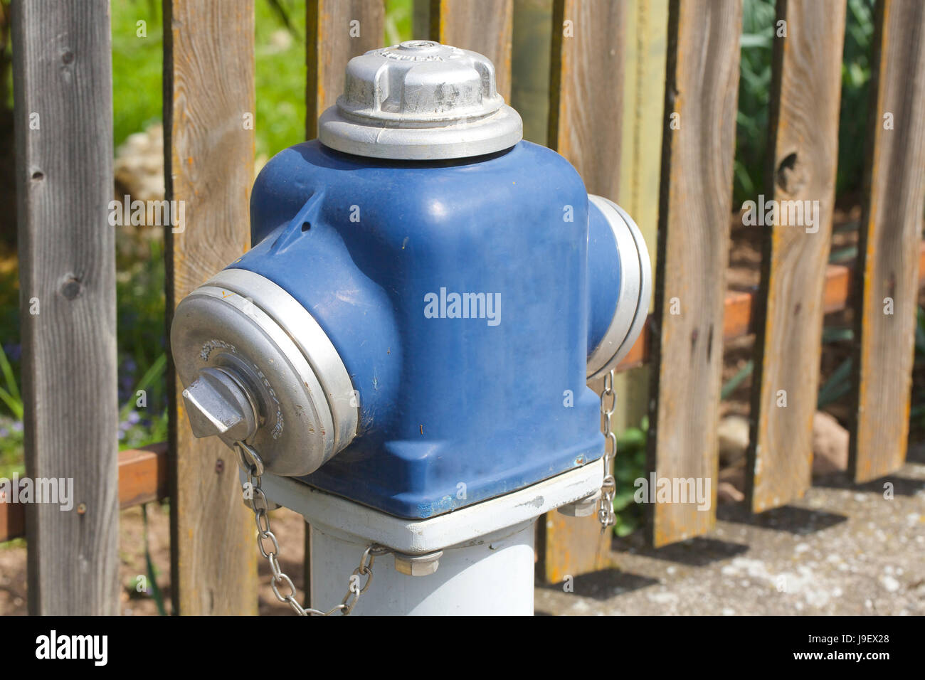 Pillar-type fire hydrant. Wooden fence in the background Stock Photo ...