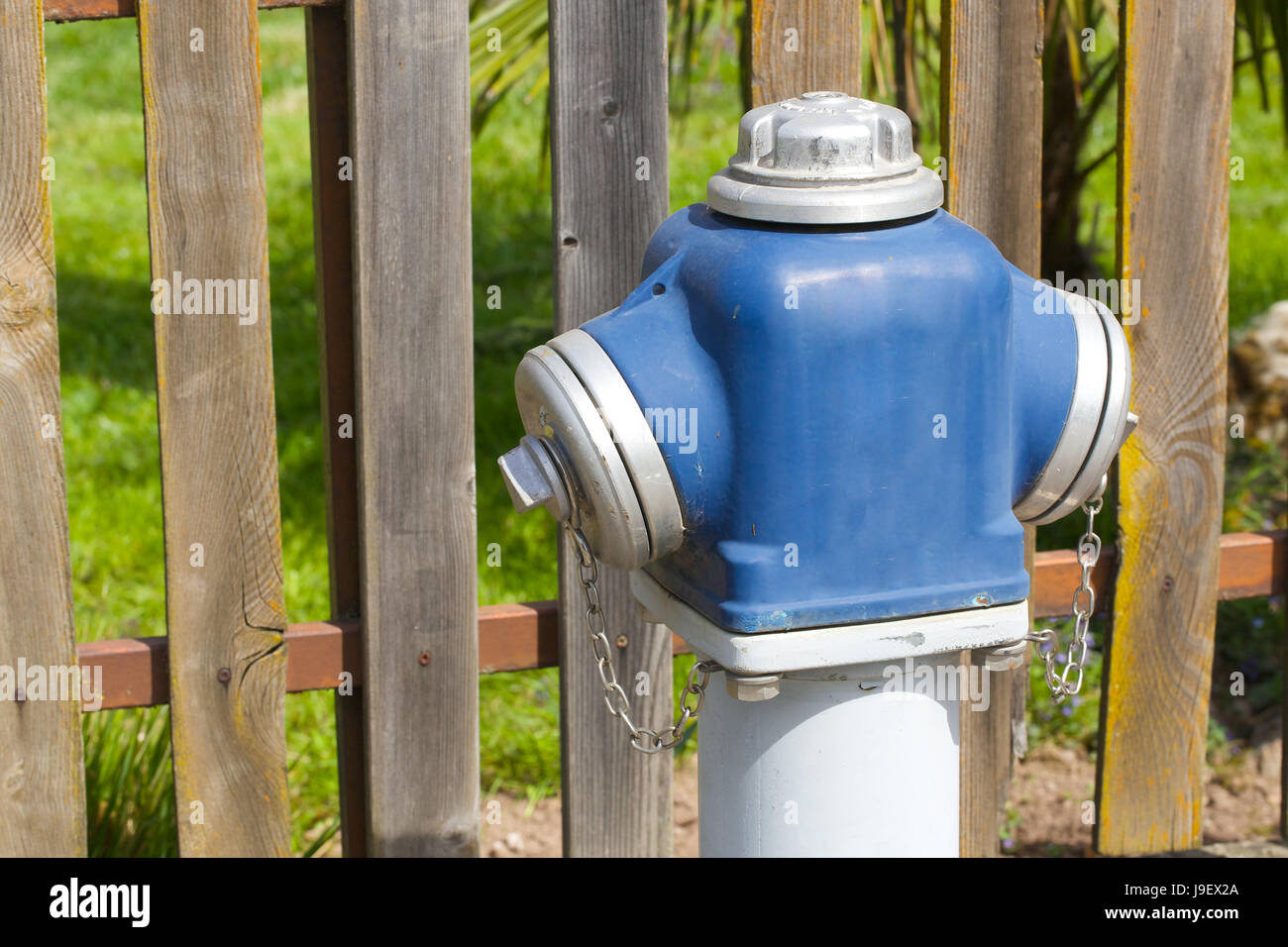 Pillar-type fire hydrant. Wooden fence in the background Stock Photo ...