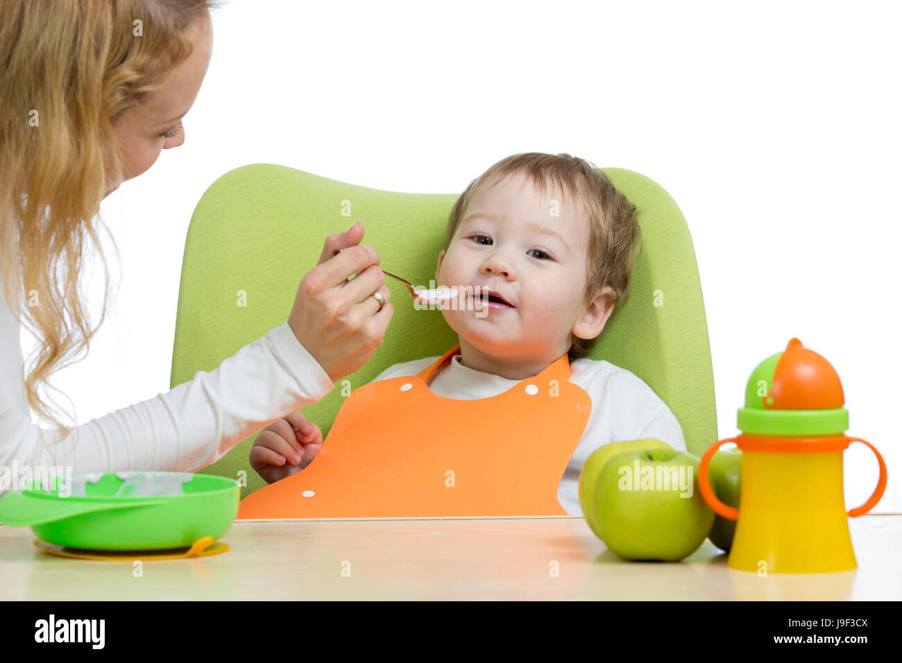 Mom feeding her kid with a spoon. Mother giving food to her little ...